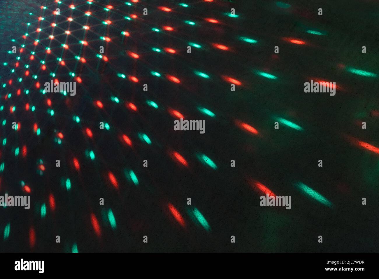 Red and green abstract patterns of light spilling across a dark surface ...