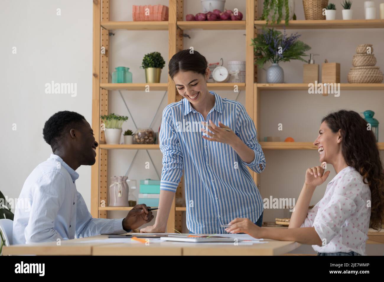 Three cheerful colleagues have fun distracted from work at workplace ...