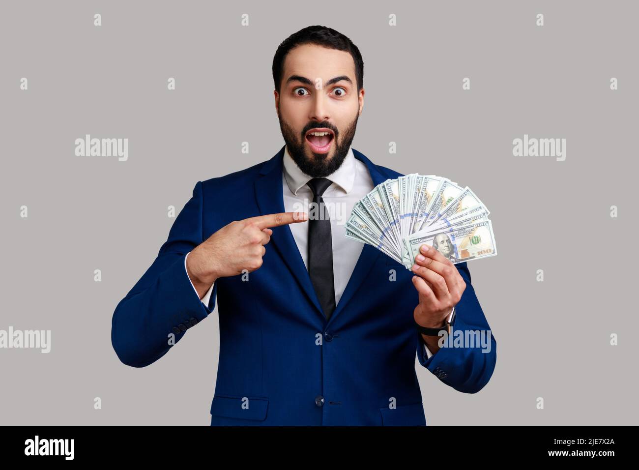 Rich bearded man pointing at dollar banknotes and looking with shocked ...