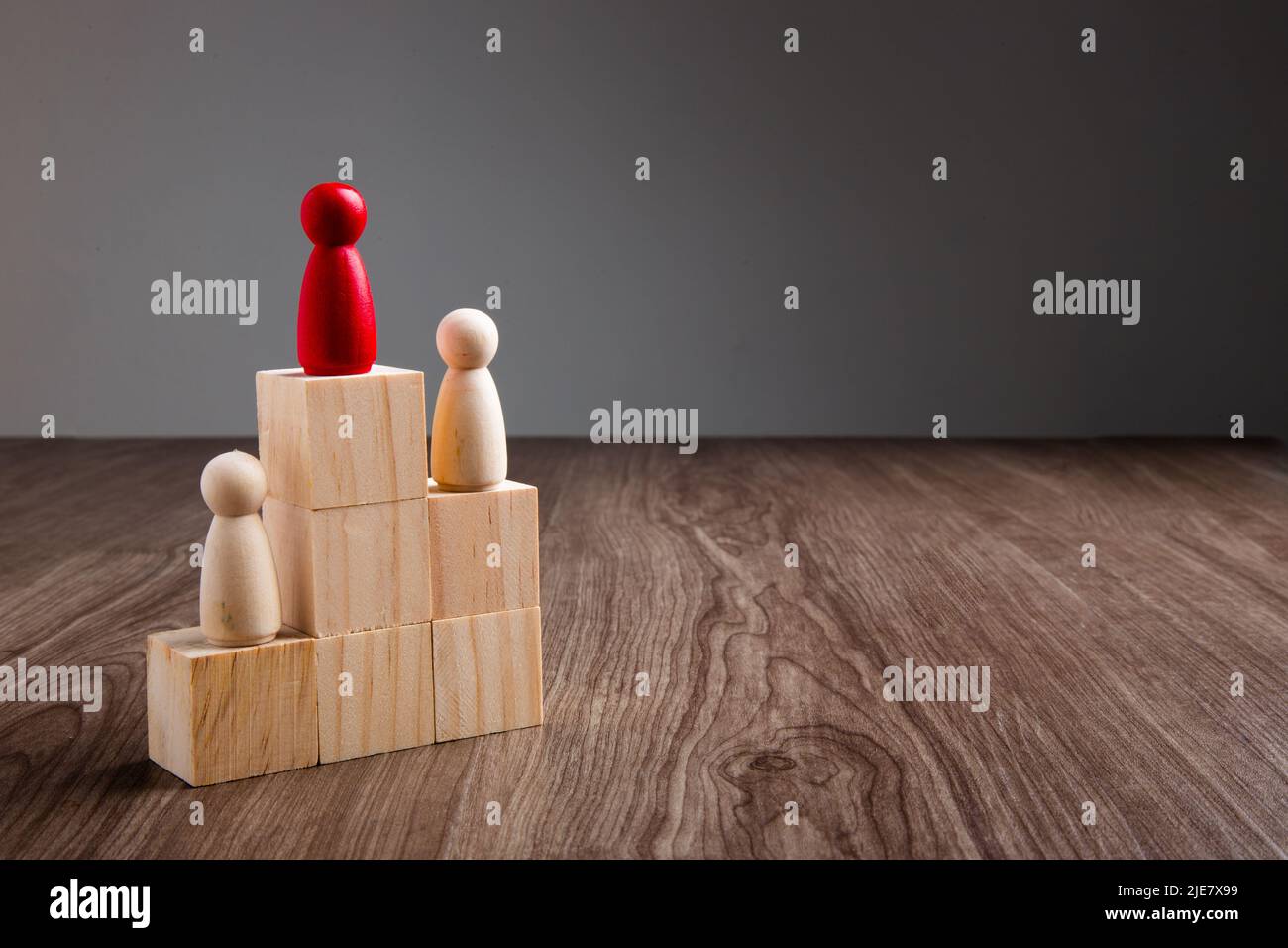 woodenl figures standing on wooden podium with business team ...