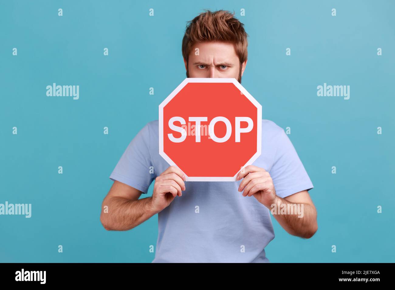 Portrait of serious strict bearded man covering half of face with red ...