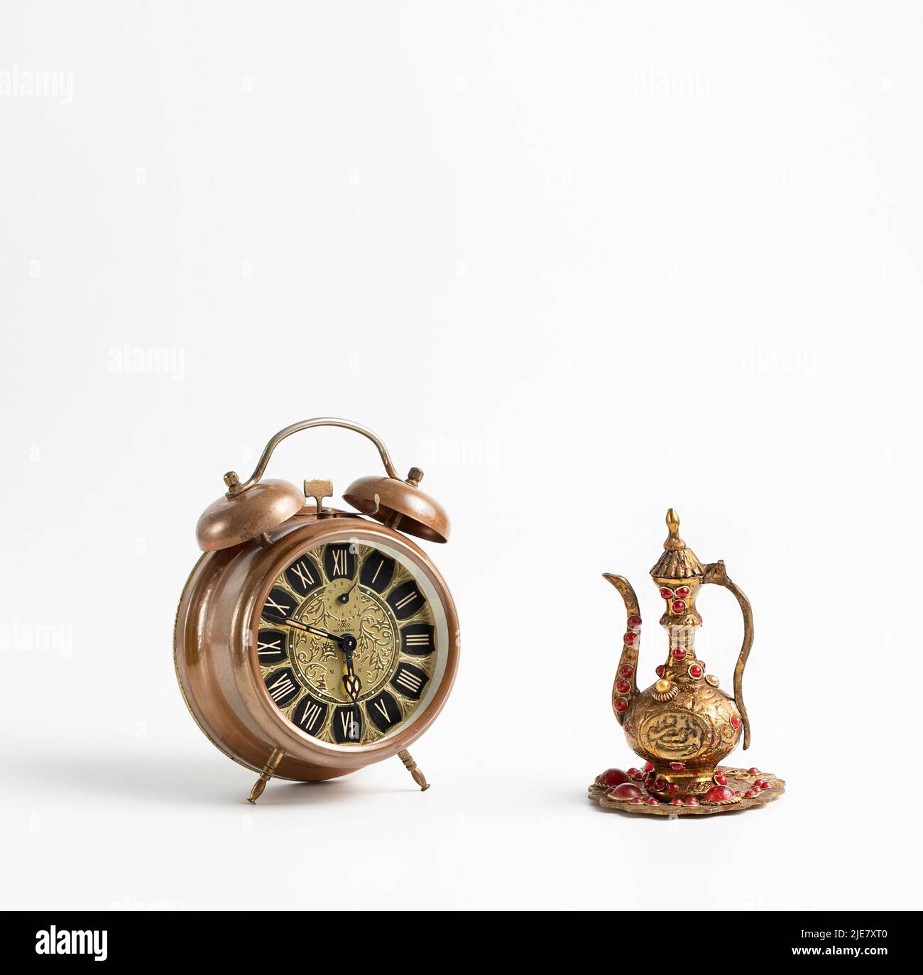 Old vintage alarm clock and small jug with stones on a white background ...