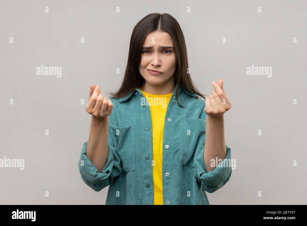 Portrait of beautiful woman makes money gesture, rubs fingers, looking ...