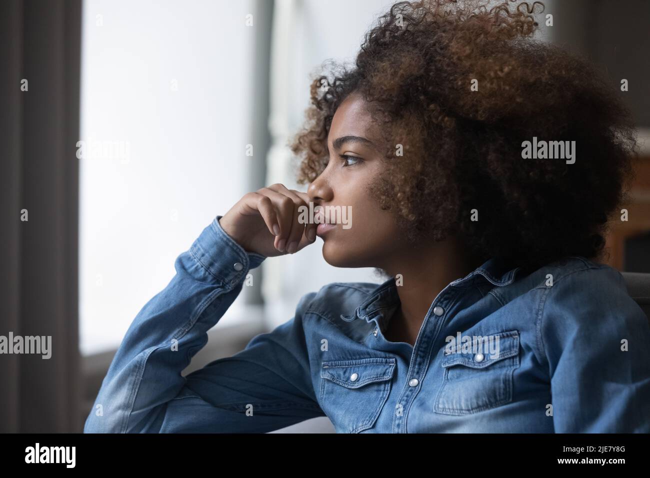Closeup face African sad thoughtful teenager girl looking into distance ...