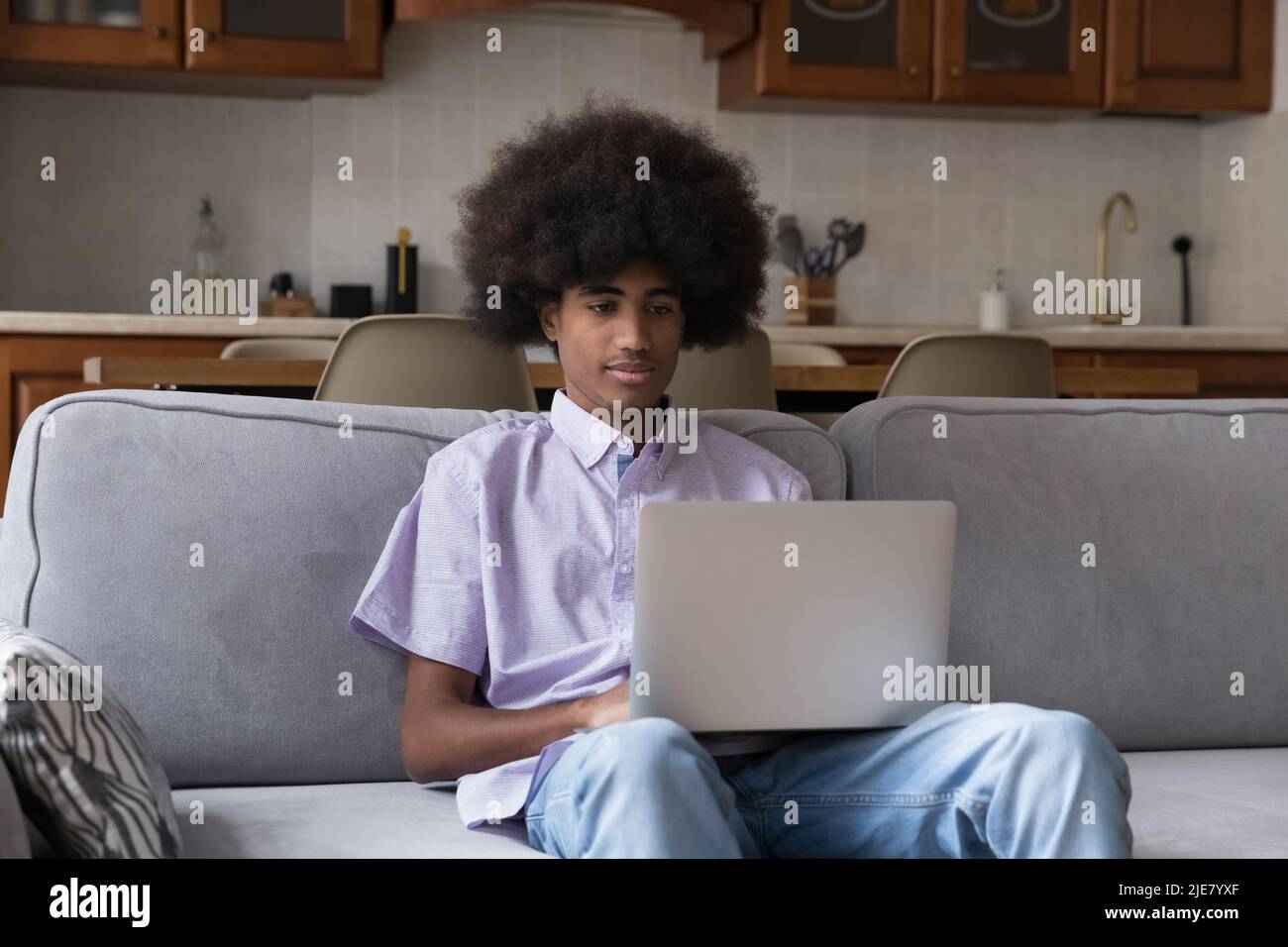 African teenage guy sit on sofa use laptop Stock Photo - Alamy
