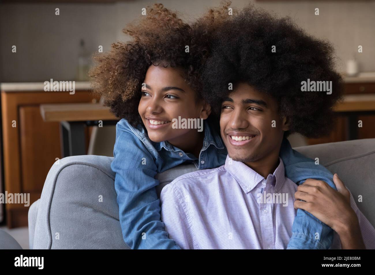 Beautiful dreamy African teenagers couple hugging staring into distance ...