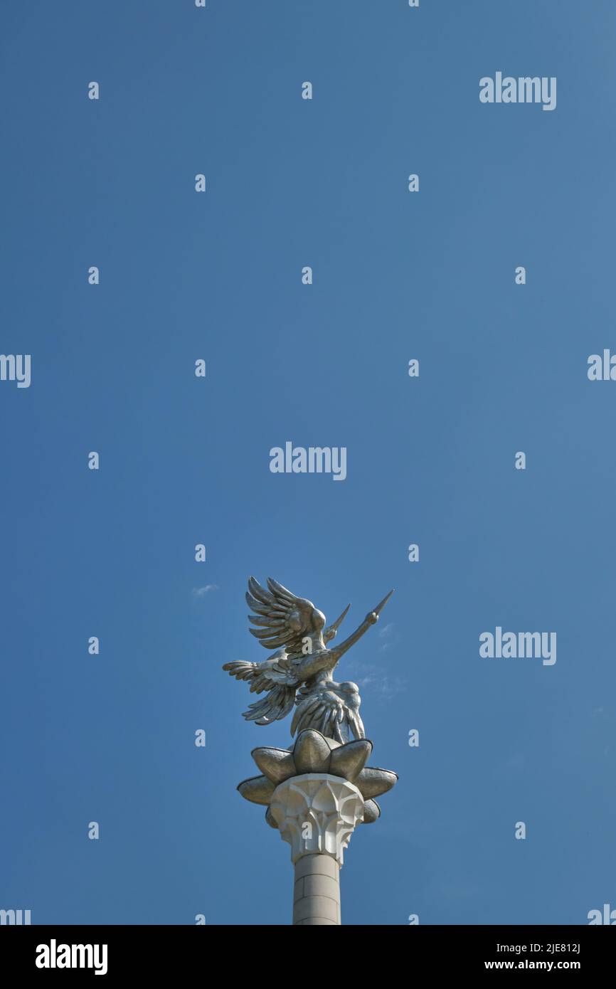 A giant, silver Humo bird sculpture on top of a column in a plaza near ...