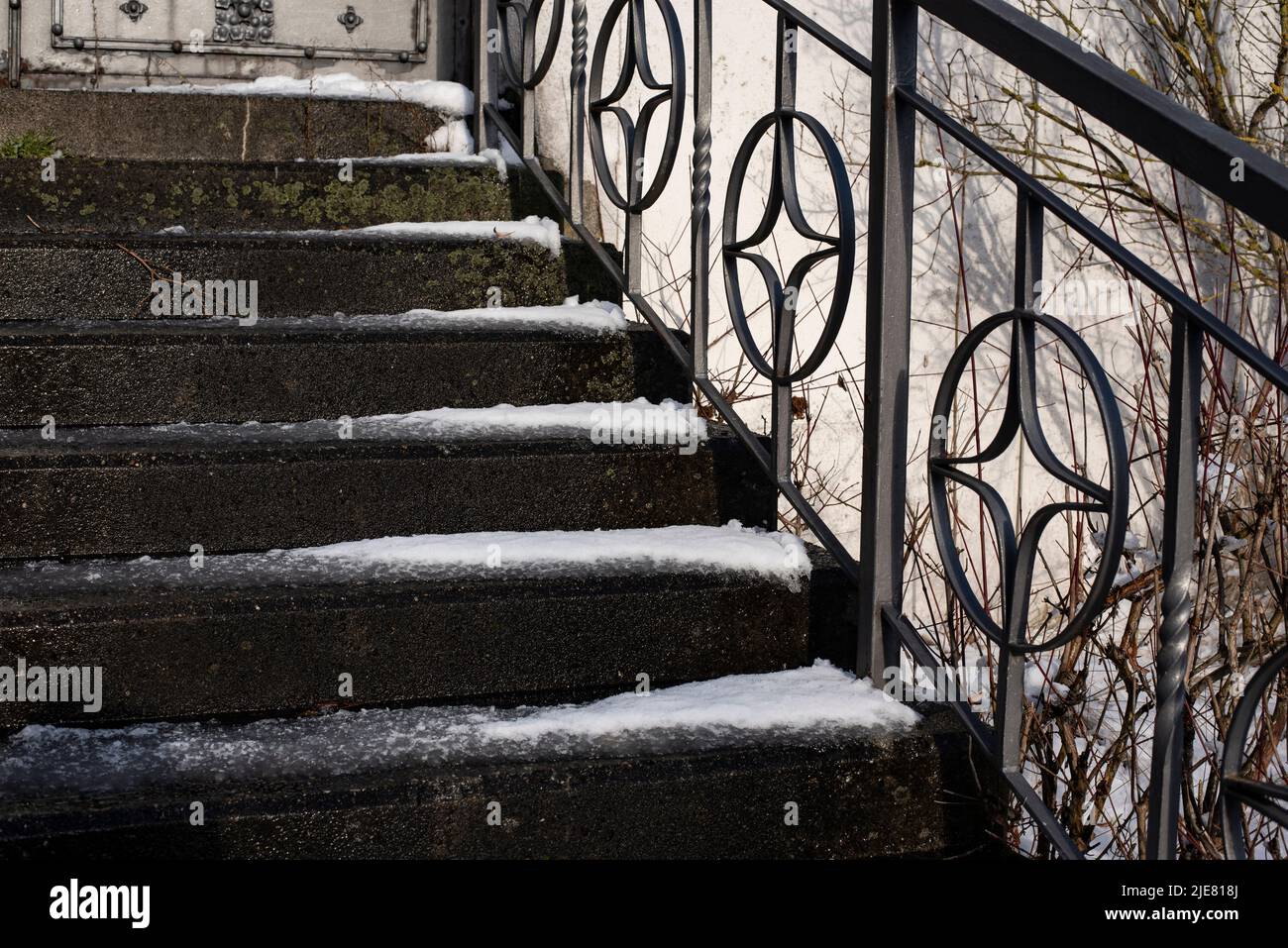 snow melting on the stone steps of a stairway with an iron railing ...