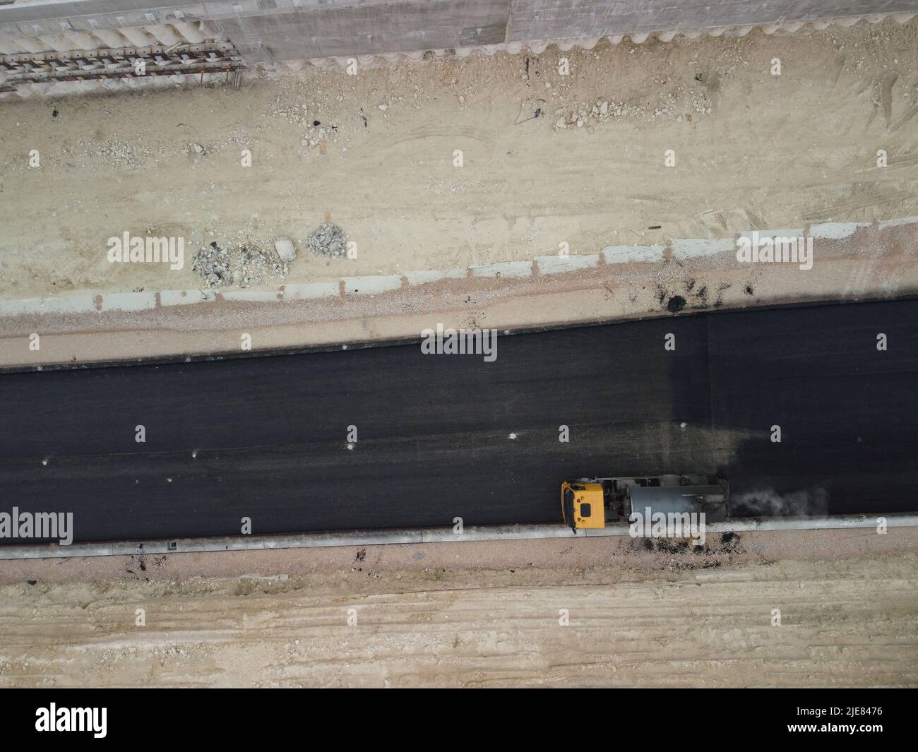 yellow truck pouring bitumen over a new road. Aerial drone shot. Road ...