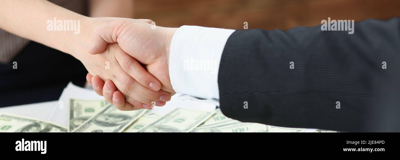 Man and woman shake hands over stack of dollars currency transaction of ...