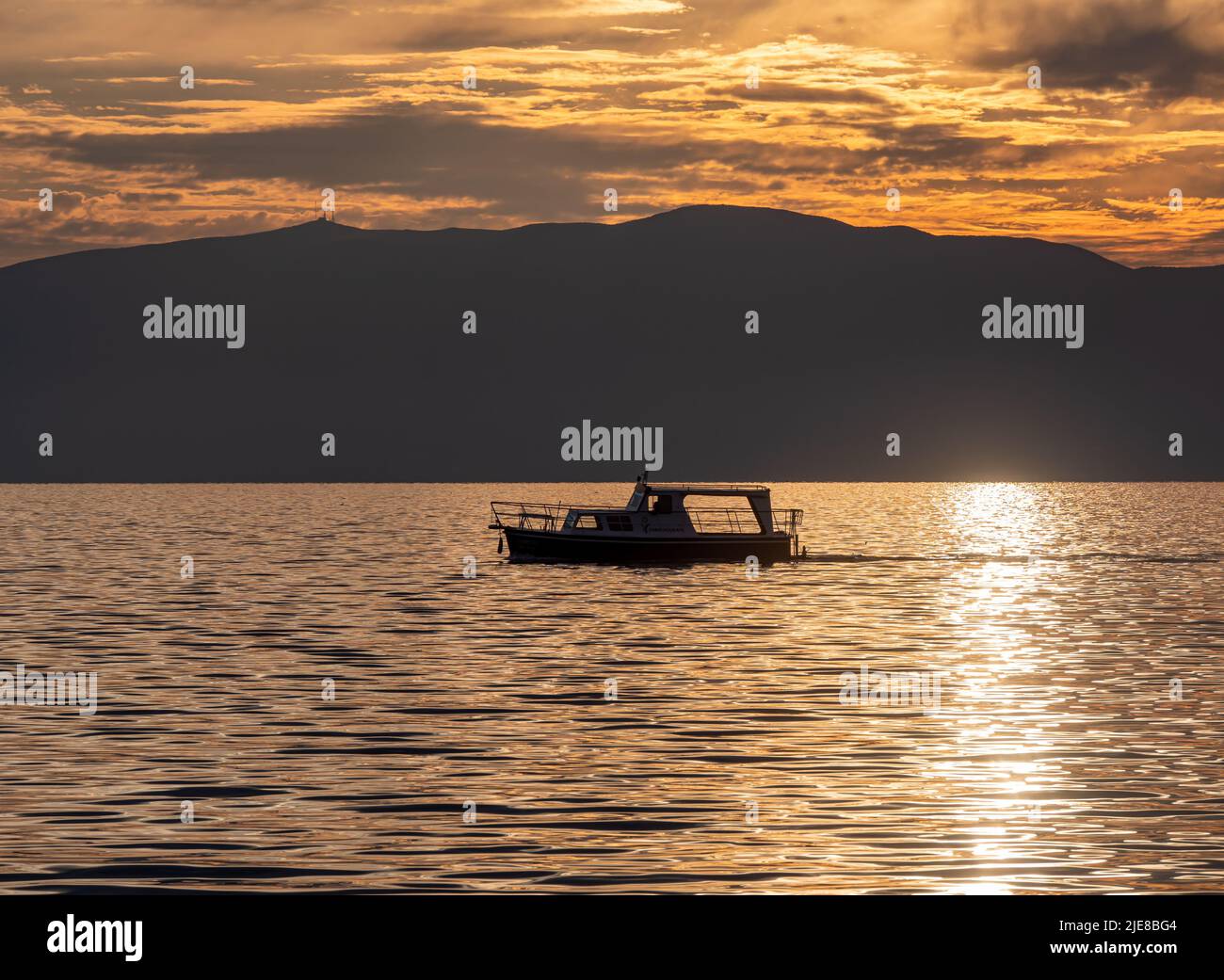 small tourist boat sails on a lake at sunset Stock Photo - Alamy