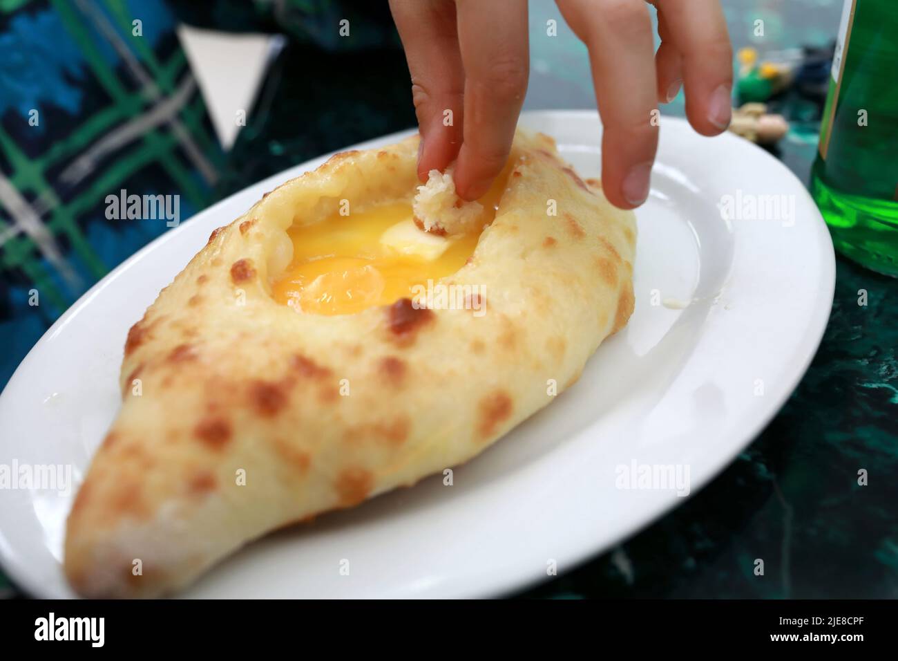 Person dipping adjarian khachapuri into yolk egg in restaurant Stock ...