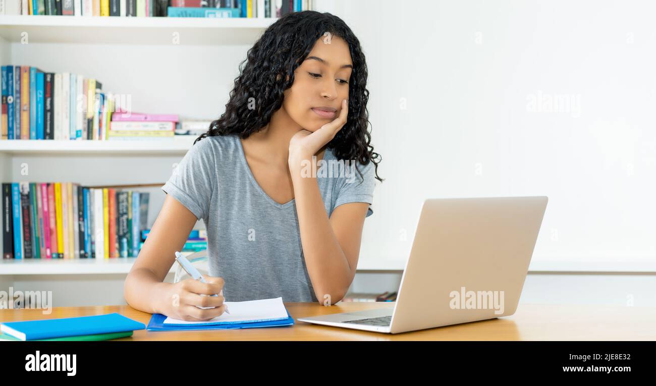 South american female student learning at desk at desk at university ...