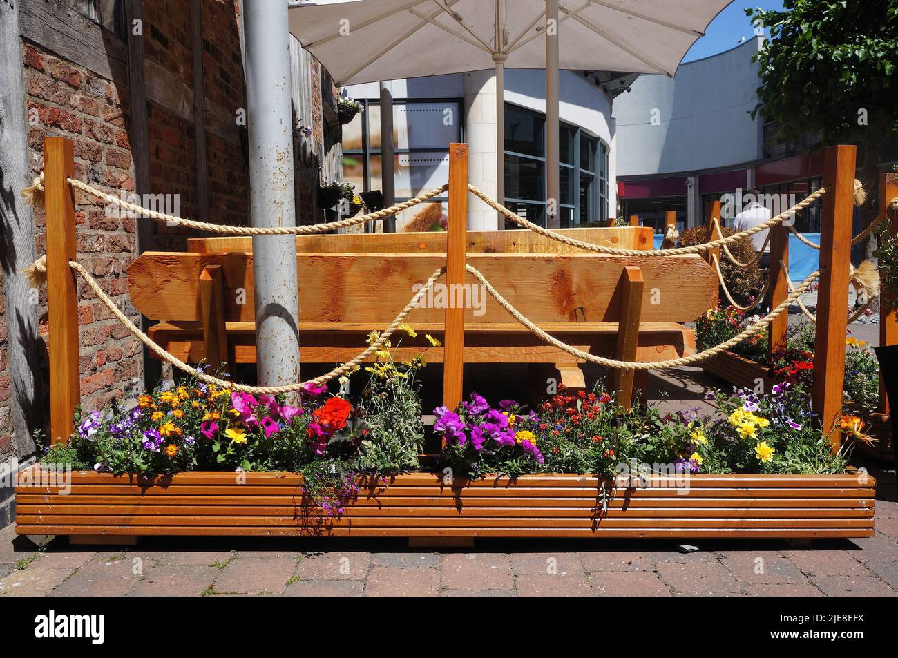 Outdoor wooden seating with decorative flower boxes in a UK shopping ...