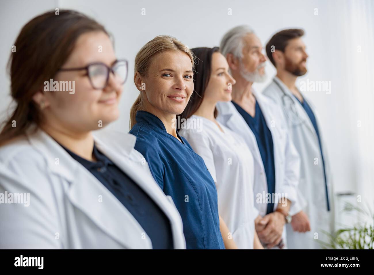 Group of doctors standing in a line and one of them looking camera at ...
