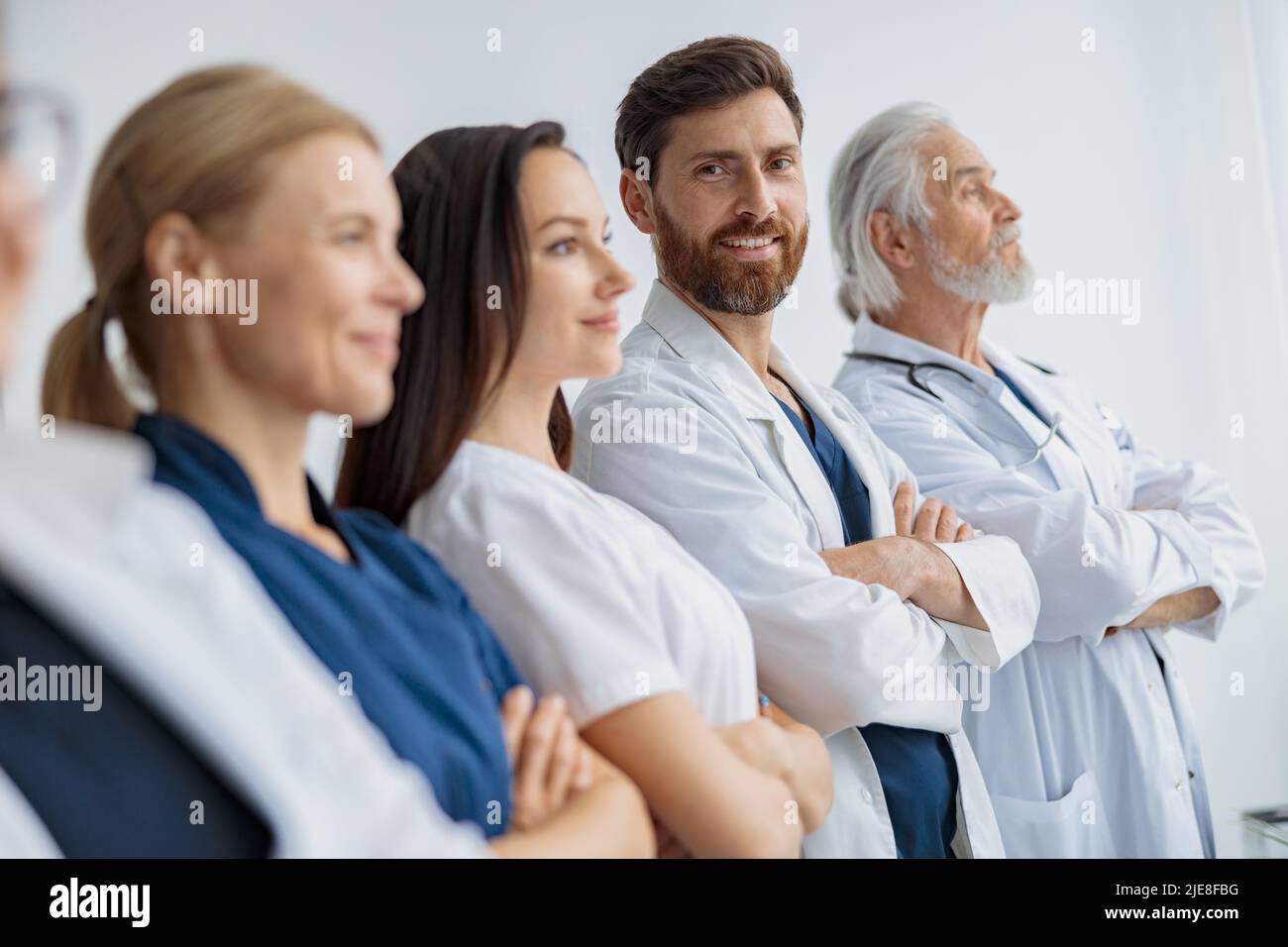 Group of professional doctors standing in a line keeping arms crossed ...