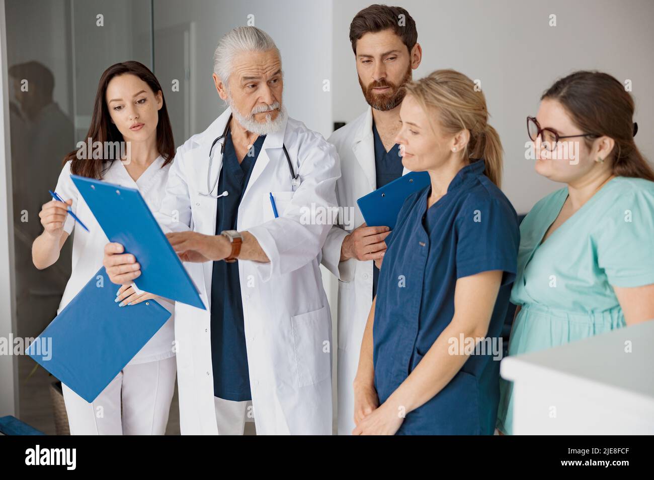 Doctor giving lecture to interns in hospital discussing patient ...