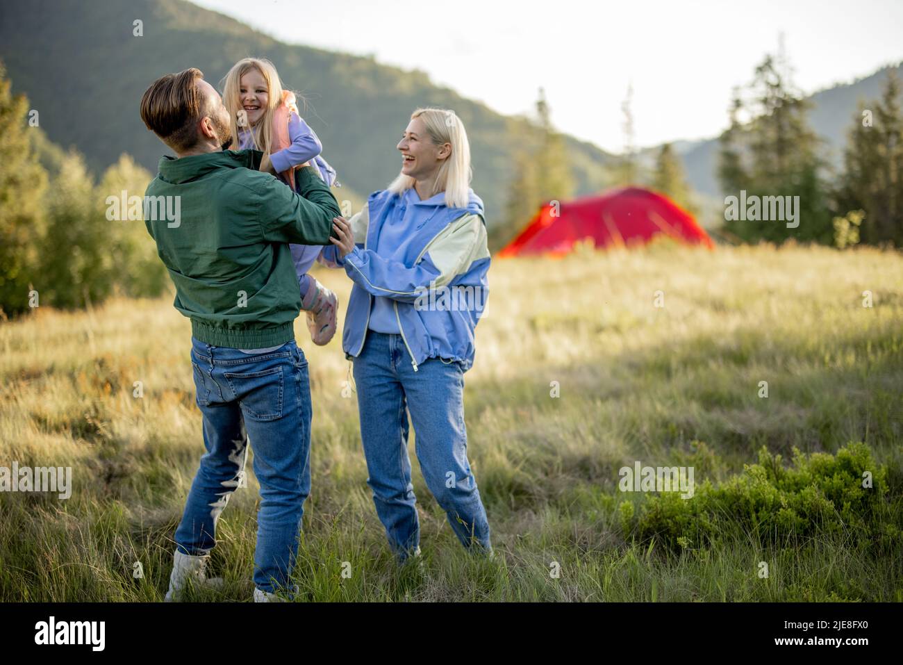 Happy couple with little girl have fun while travel in the mountains ...