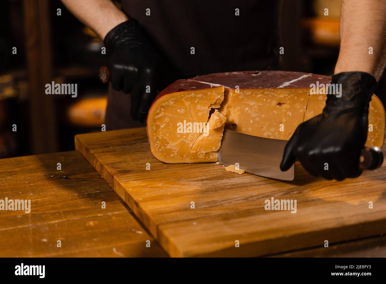Cheese sommelier cutting limited gouda cheese with knife. Snack tasty ...