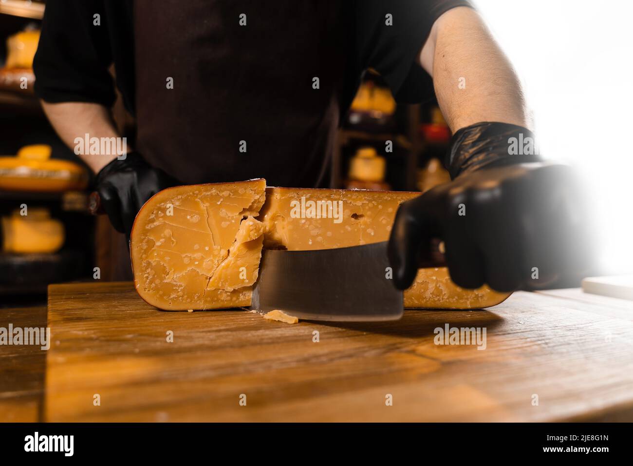 Cut limited gouda cheese with knife. Cutting cheese in store. Snack ...