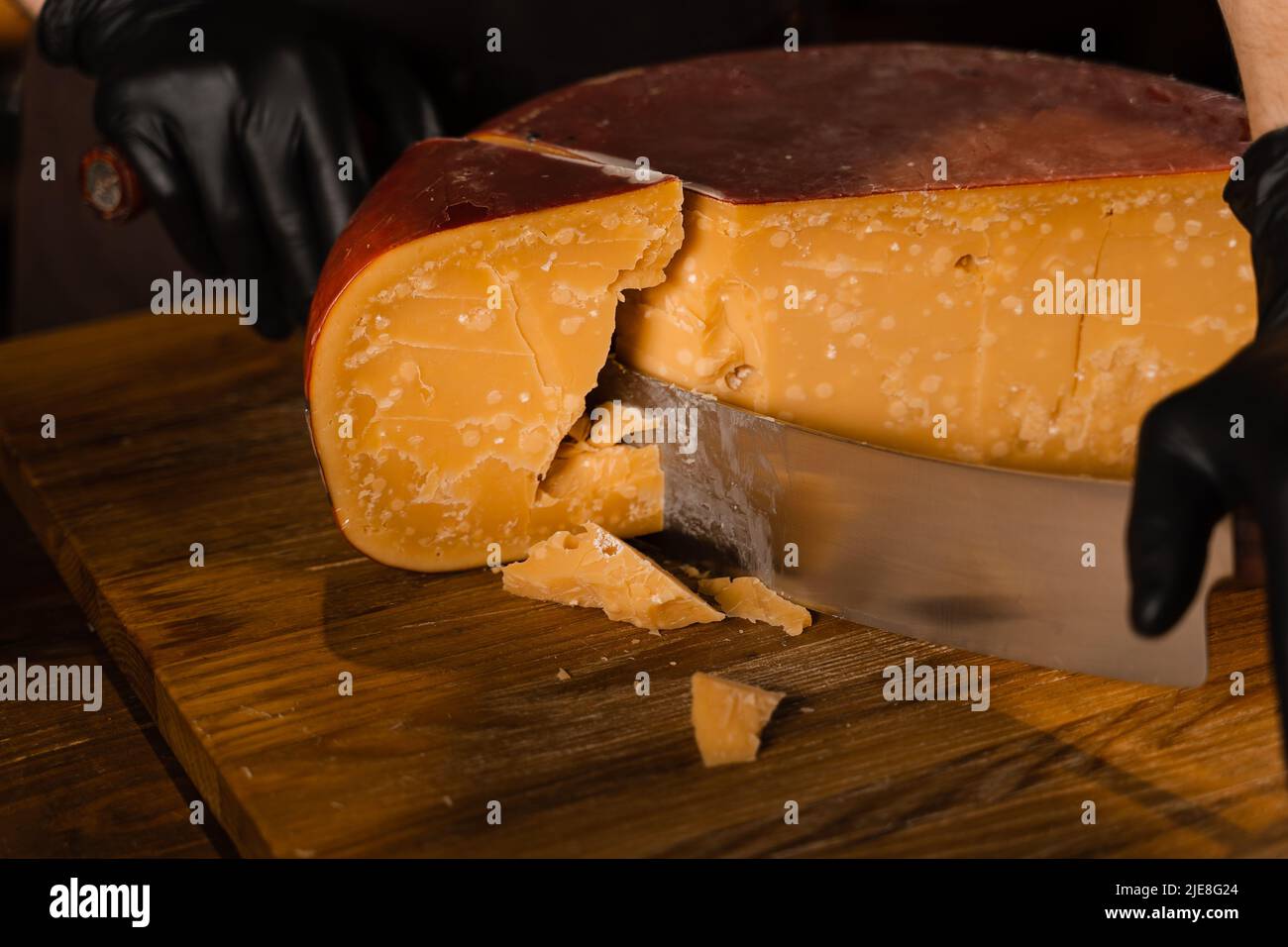 Cut limited gouda cheese with knife close-up. Cutting cheese in store ...