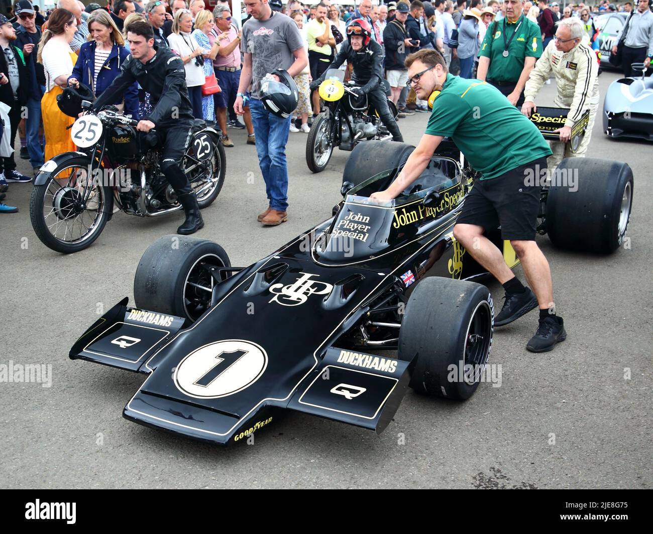 A JPS Lotus Grand Prix car is pushed by mechanics in the paddock at the ...
