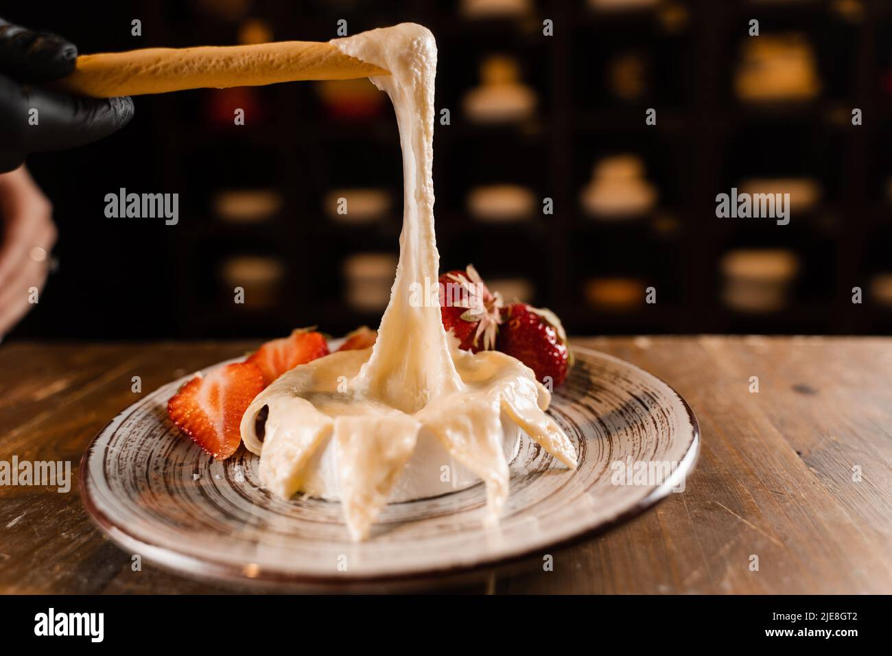 Eating hot baked camembert cheese with grissini sticks. Stretching ...