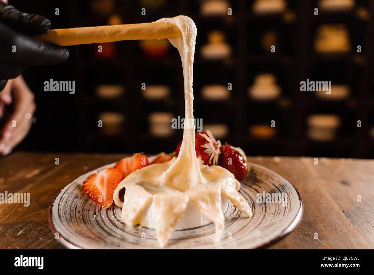 Eating hot baked camembert cheese with grissini sticks. Stretching ...