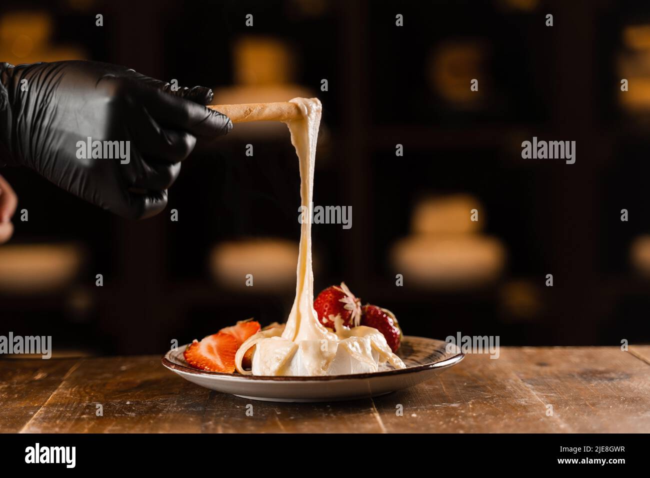 Eating hot baked brie cheese with grissini sticks. Stretching melted ...