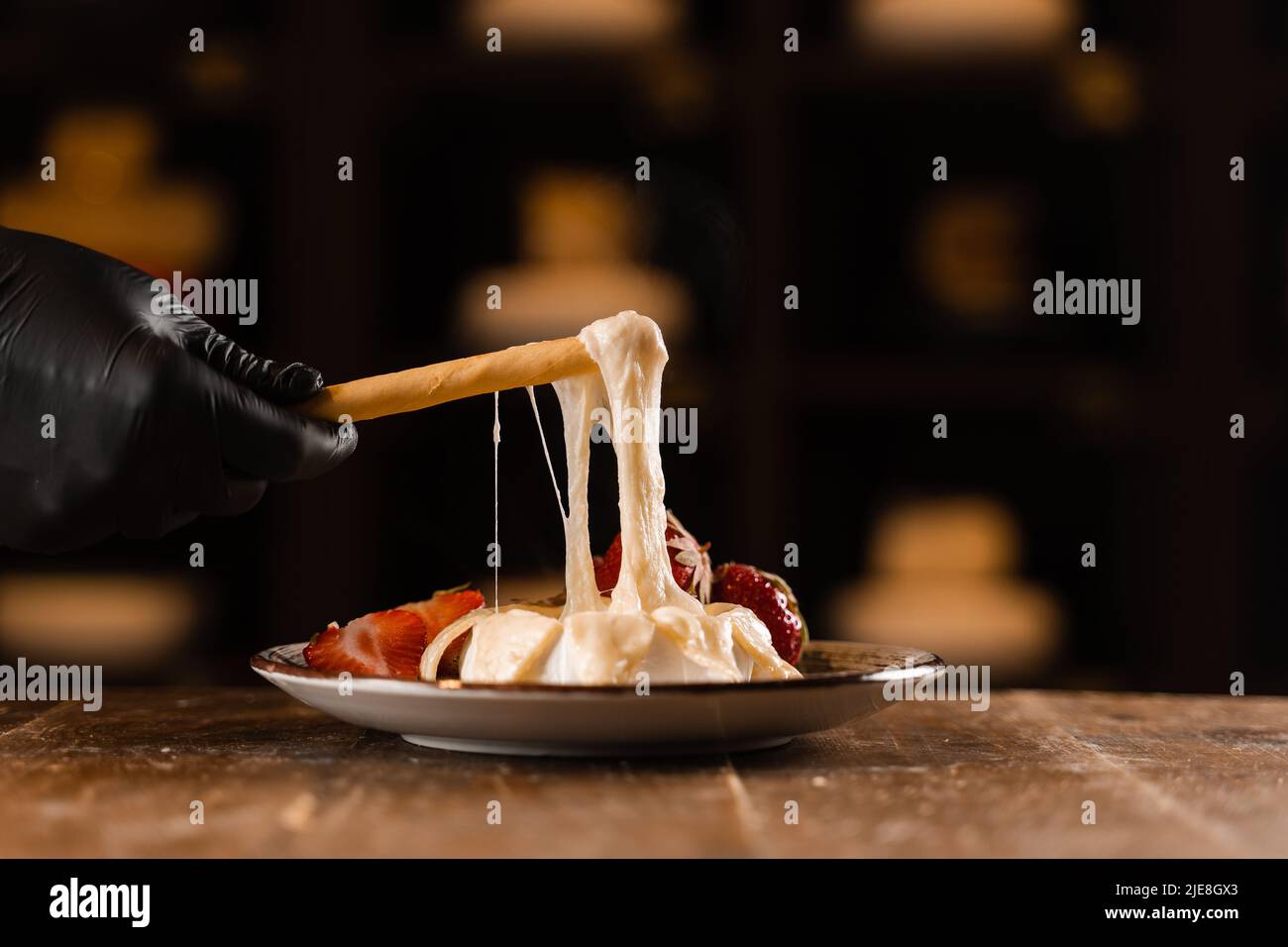 Eating hot baked brie cheese with grissini sticks. Stretching melted ...