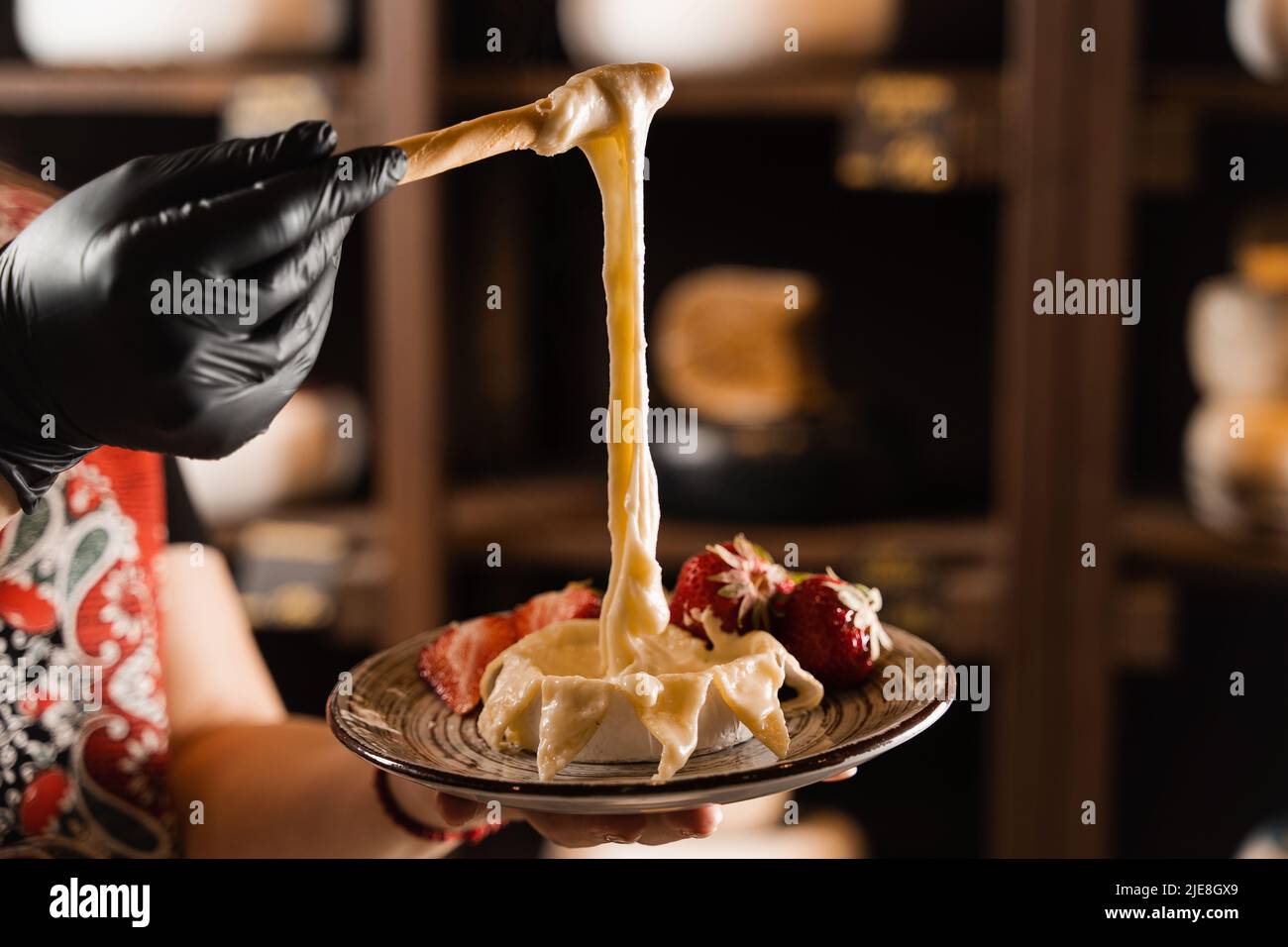 Eating hot baked camembert cheese with grissini sticks. Stretching ...