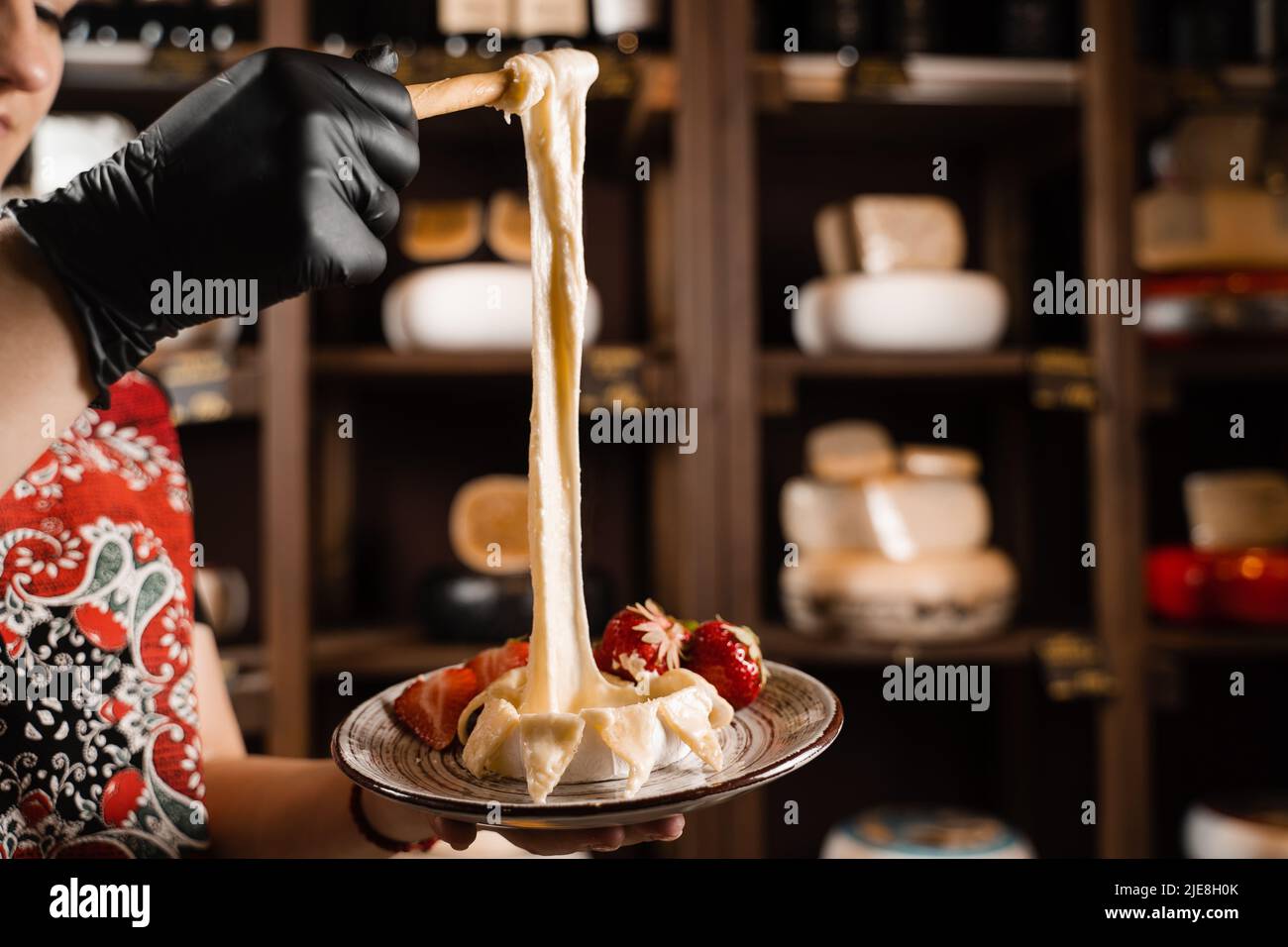 Eating hot baked camembert cheese with grissini sticks. Stretching ...