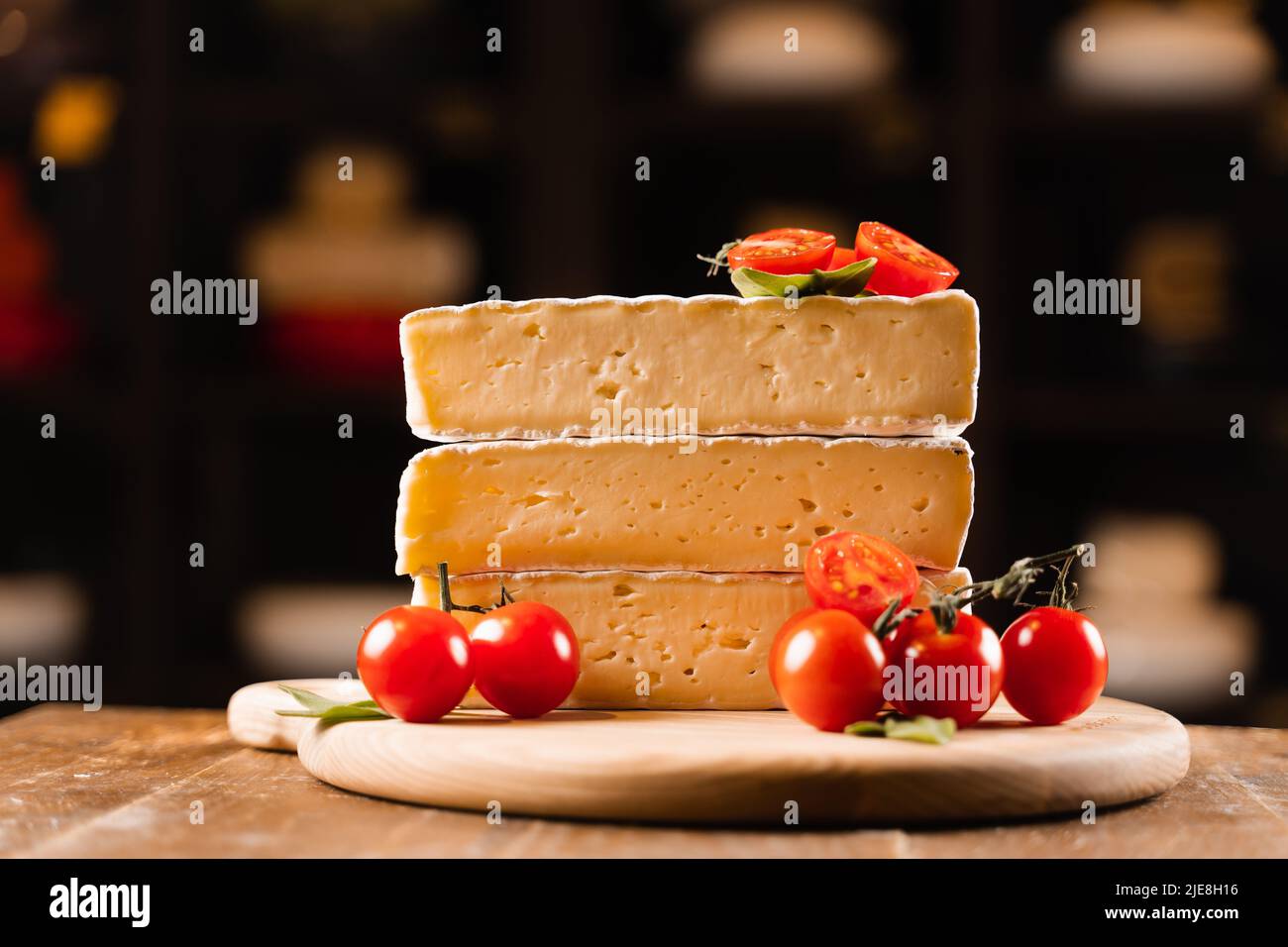Brie cheese with tomatoes on the wooden plate in cheese store. Creative ...