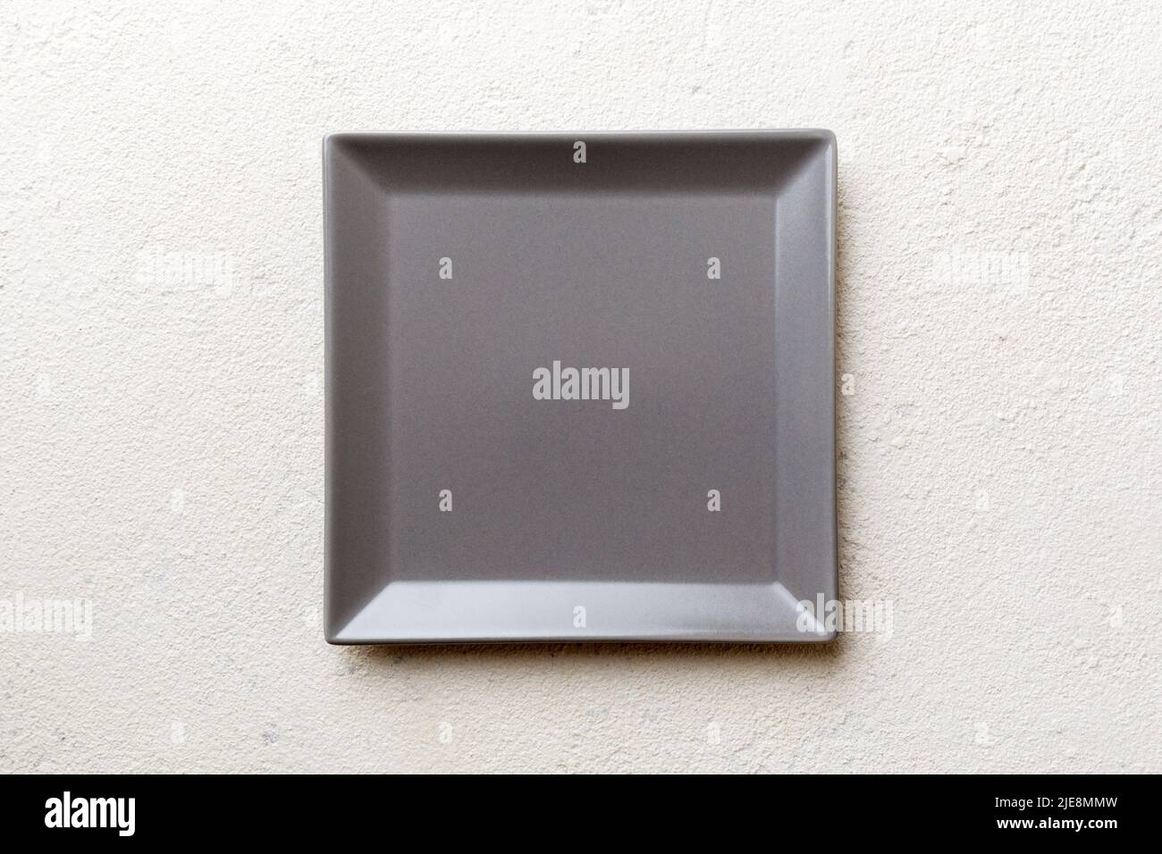 Top view of empty square plate on cement background. Empty space for ...