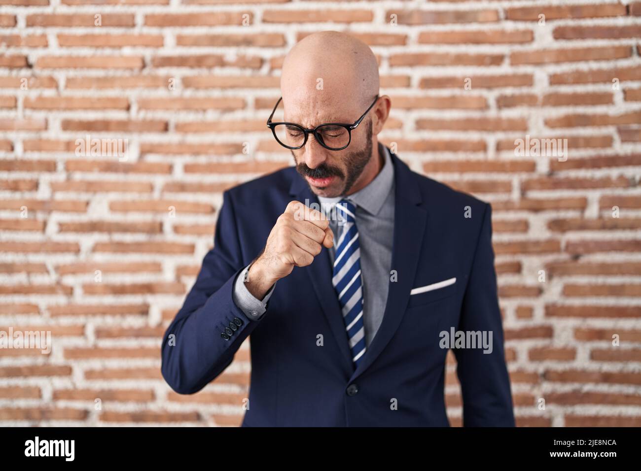 Bald man with beard wearing business clothes and glasses feeling unwell ...