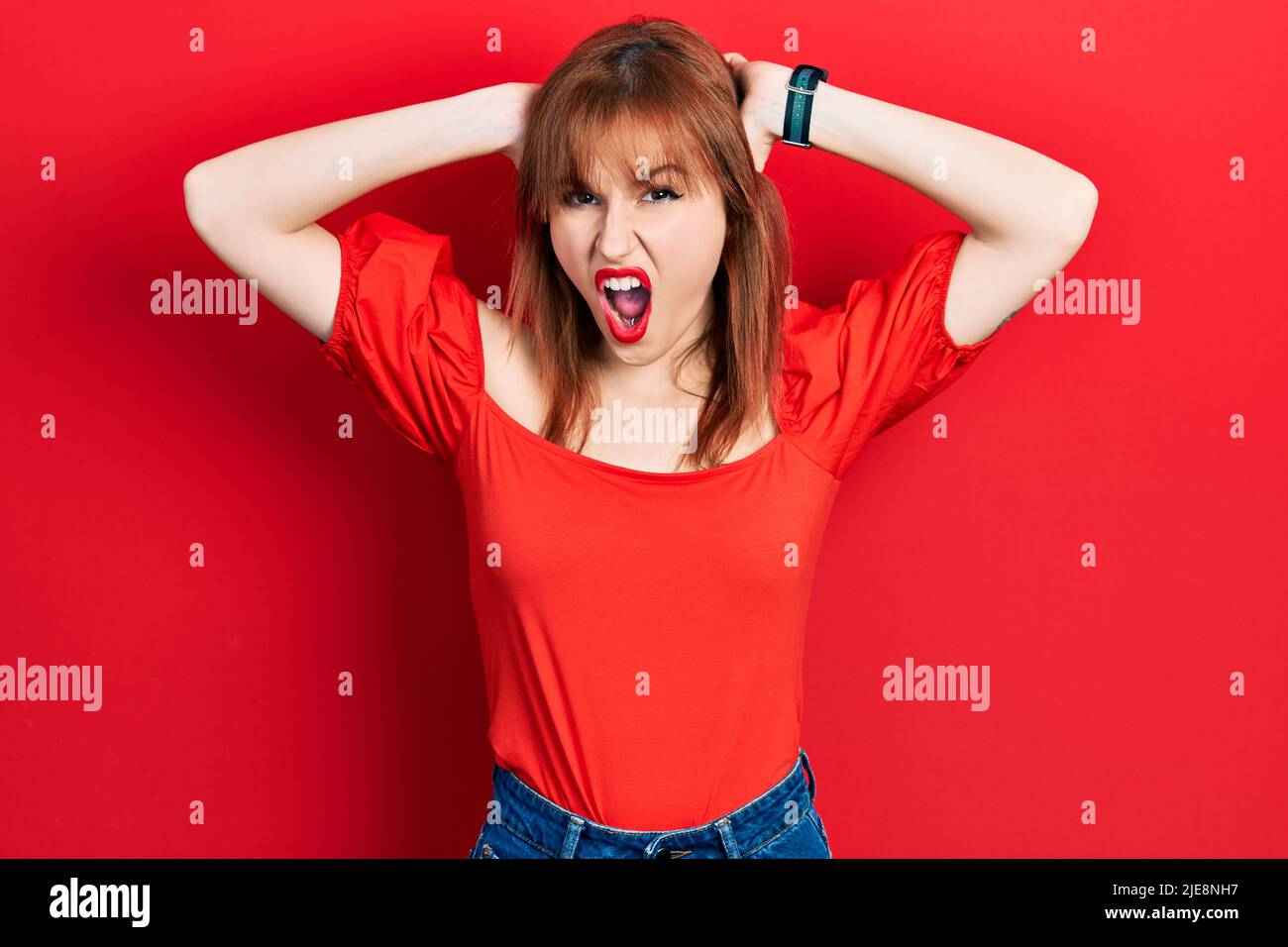 Redhead young woman wearing casual red t shirt crazy and scared with ...