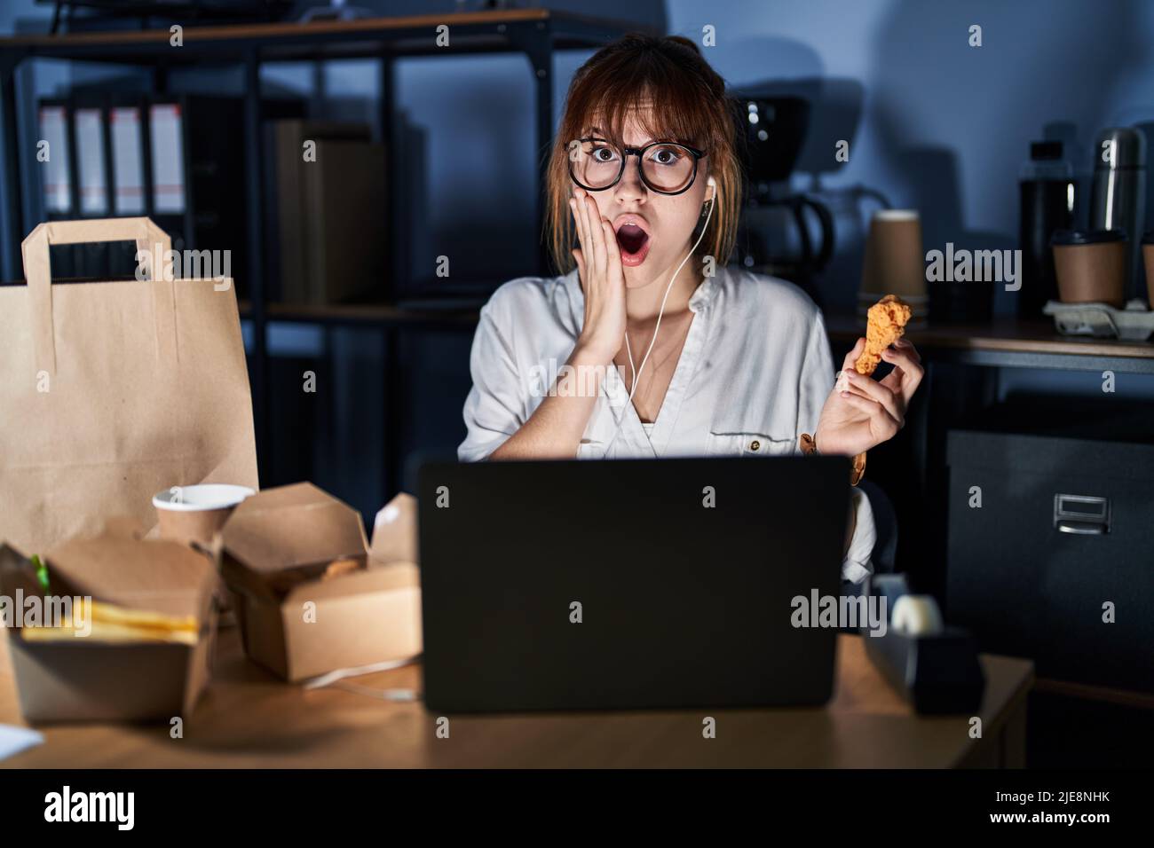 Young beautiful woman working using computer laptop and eating delivery ...