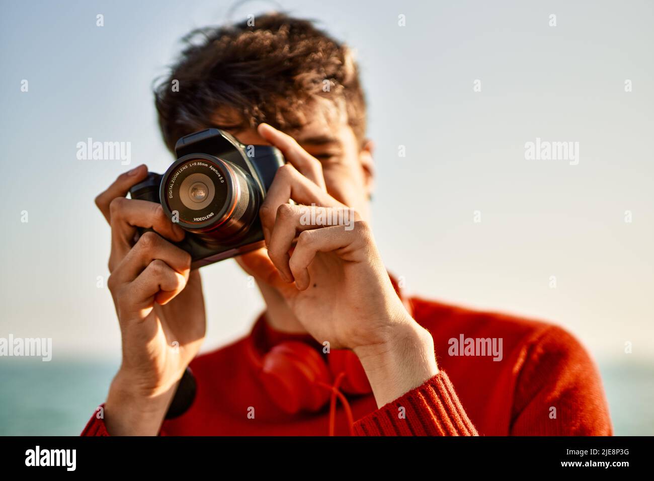 Young hispanic man smiling happy using reflex camera at the beach Stock ...