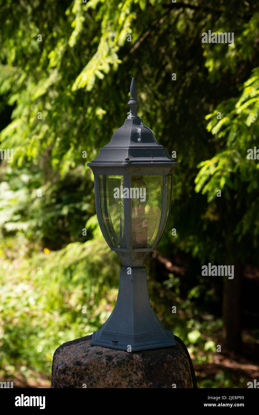 An old-fashioned metal light lantern that stands on a large boulder in ...