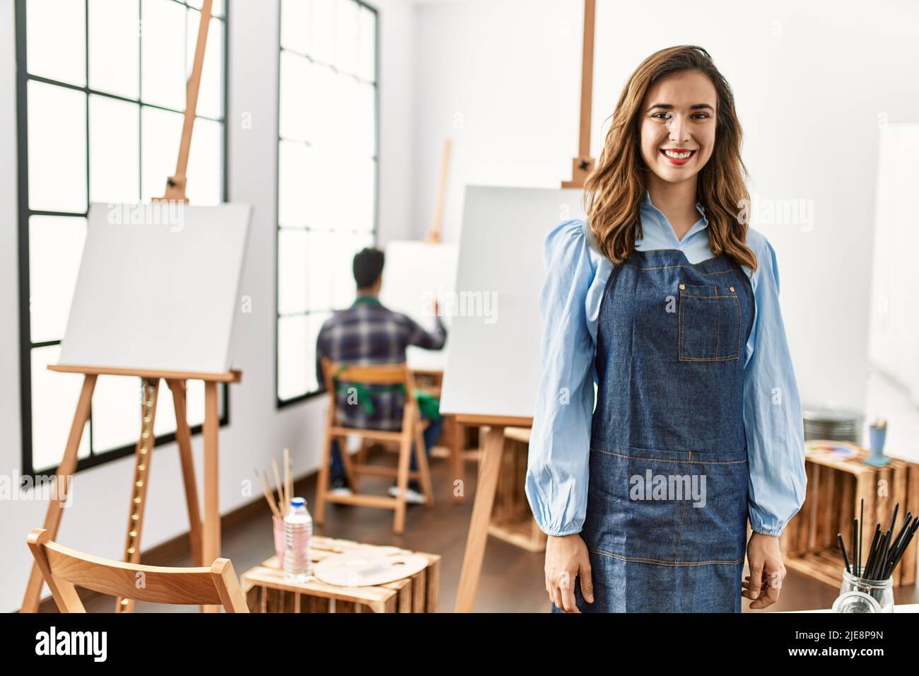Young artist woman at art studio with a happy and cool smile on face ...