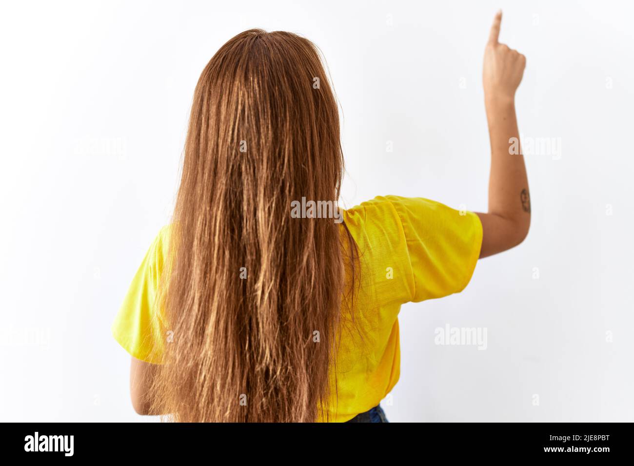 Young brunette woman standing over isolated background posing backwards ...