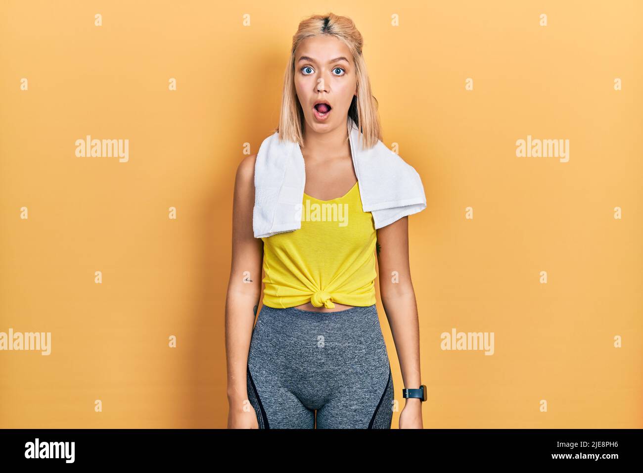 Beautiful blonde sports woman wearing workout outfit afraid and shocked ...