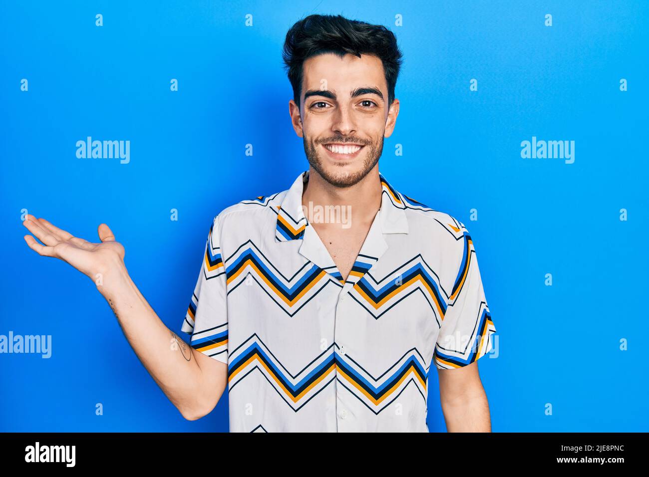 Young hispanic man wearing casual clothes smiling cheerful presenting ...