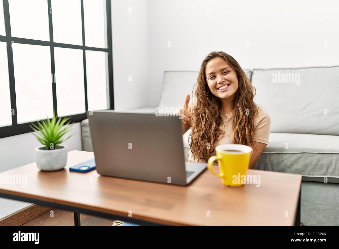 Beautiful hispanic woman using computer laptop at home smiling happy ...