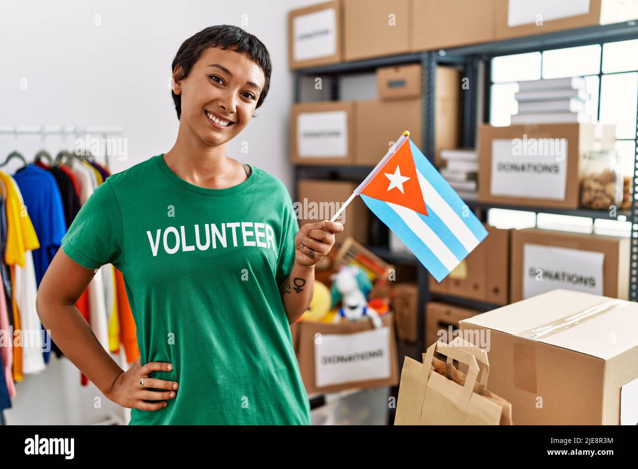 Young hispanic woman wearing volunteer uniform holding cuba flag at ...
