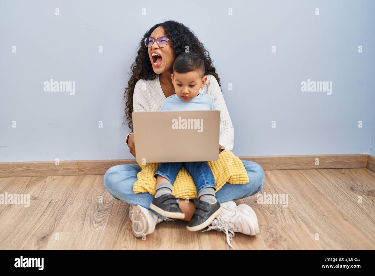 Young hispanic mother and kid using computer laptop sitting on the ...