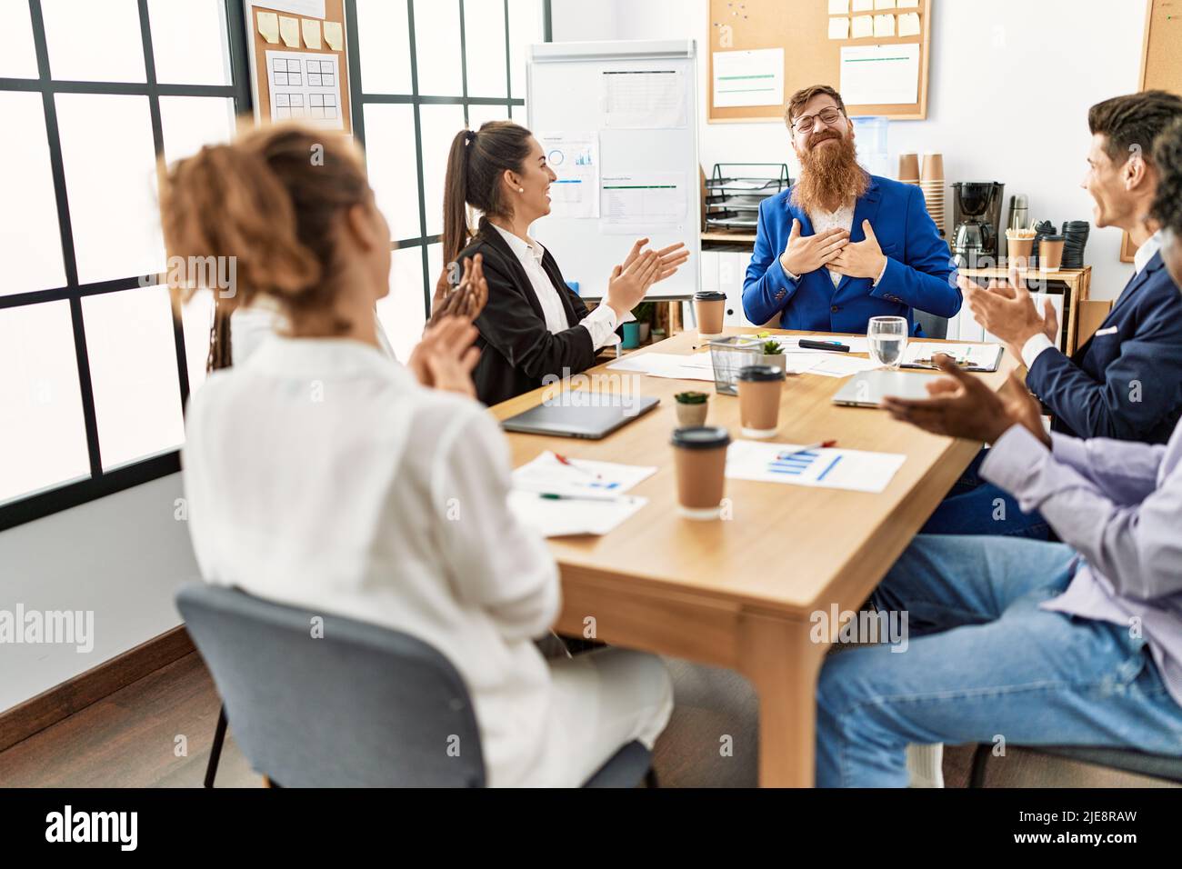Group of business workers smiling and clapping to partner at the office ...