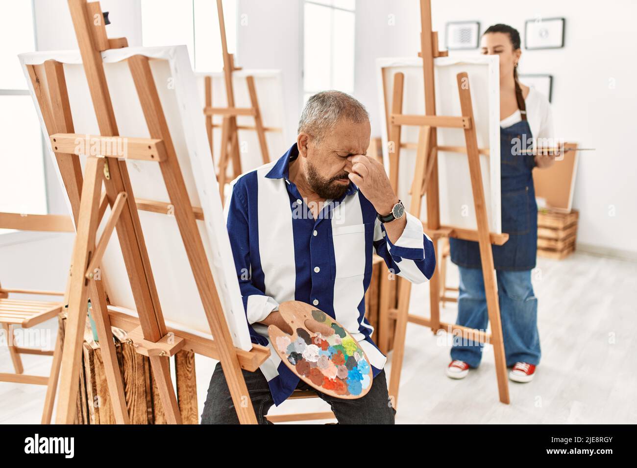 Senior artist man at art studio tired rubbing nose and eyes feeling ...