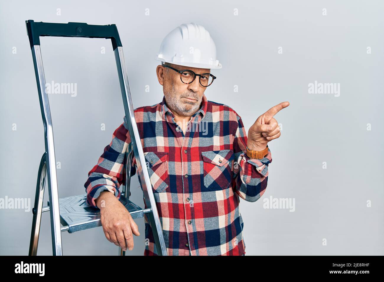 Handsome mature handyman close to construction stairs wearing hardhat ...