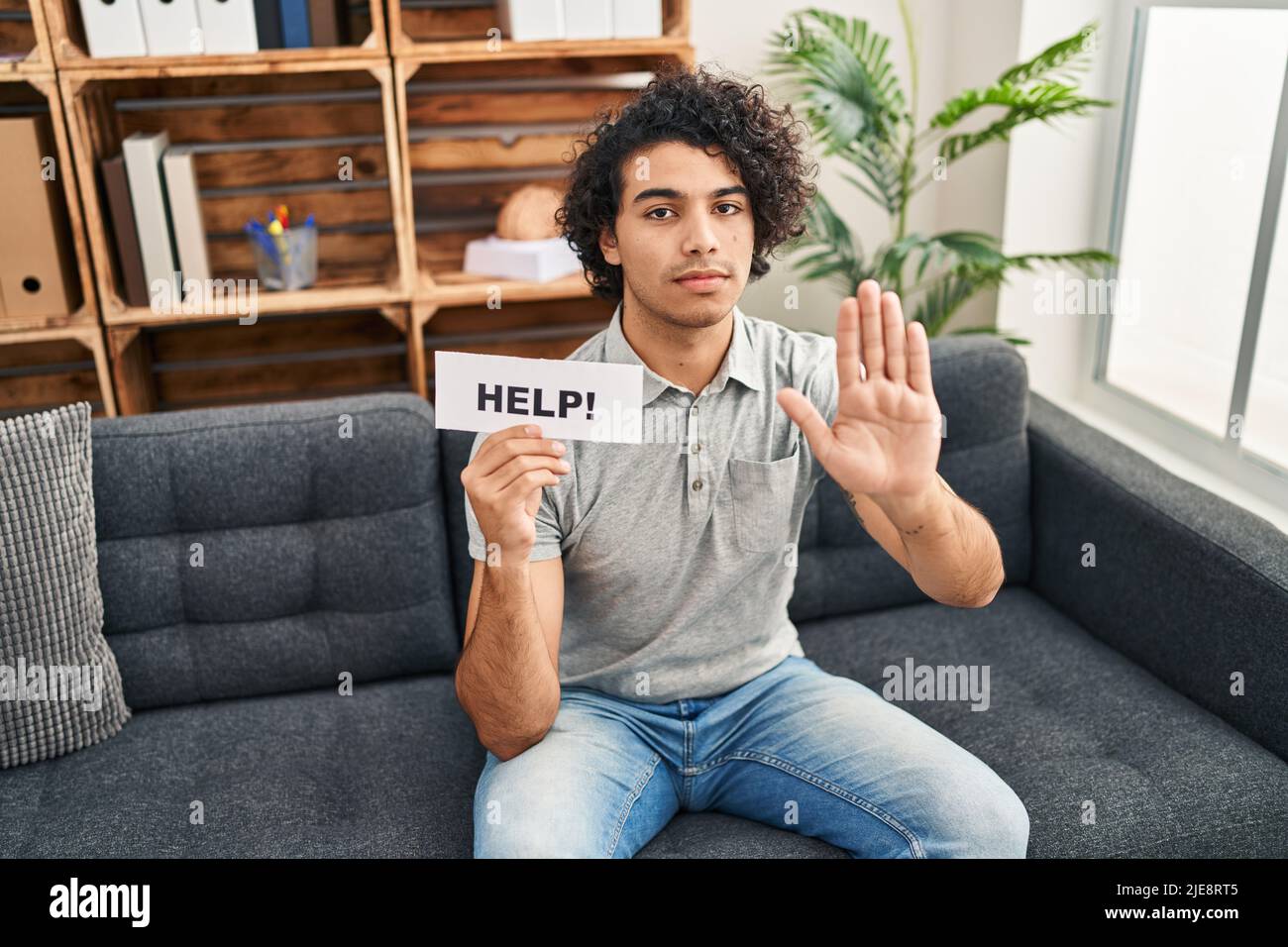 Hispanic man with curly hair asking for help with open hand doing stop ...